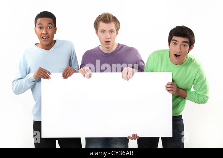 Three surprised men holding poster Stock Photo - Alamy