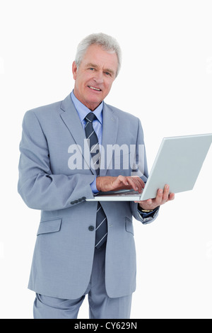 Mature tradesman holding and looking at laptop screen Stock Photo - Alamy