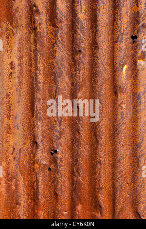 Weathered corrugated metal wall with rust and aged paint creating an ...