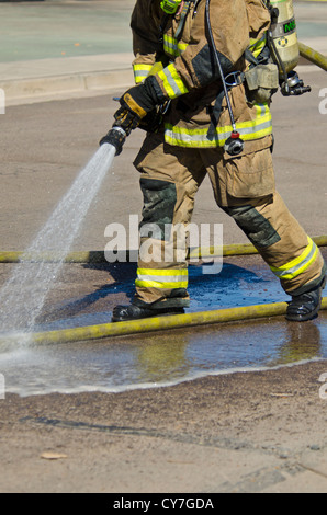 Firefighter man, water and spraying hose for emergency, rescue or ...