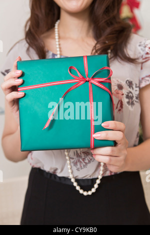 Woman with Christmas tree holding gift on blue background Stock Photo ...