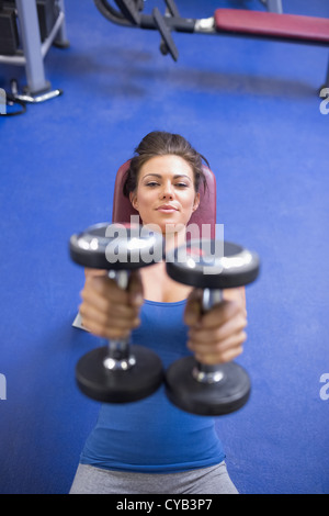Focused young woman straining to lift a barbell with friends cheering ...
