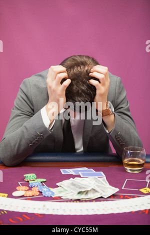 A young depressed male gambler at the gambling table gun and drugs in ...