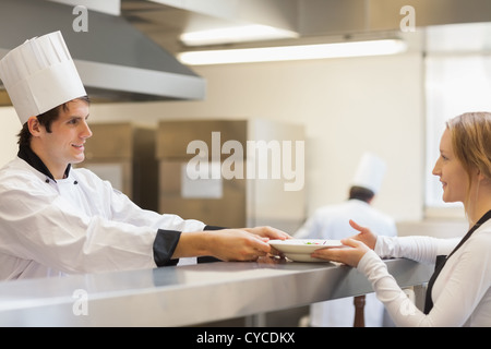 Chef passing plate to waitress Stock Photo - Alamy