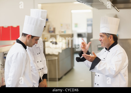 Exasperated head chef scolding upset female employee in kitchen of ...