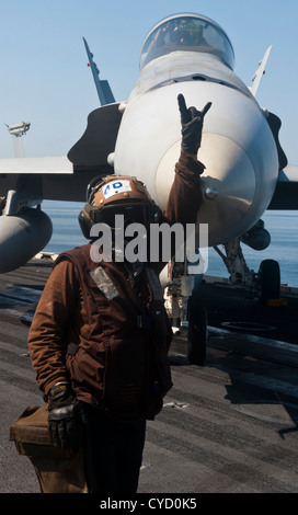 A plane captain signals an aircraft to move forward on the catapult ...