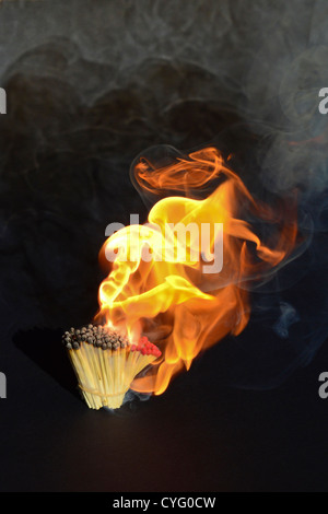 A bundle of matches alight on a black background Stock Photo - Alamy