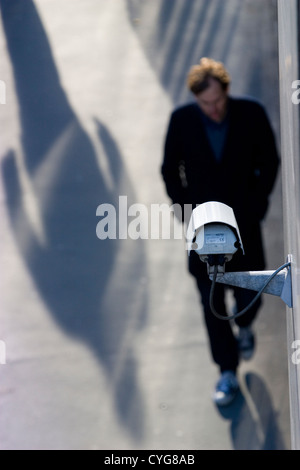 A surveillance CCTV camera watches over a passing commuter, their ...