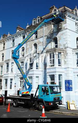 Workmen using a cherry picker to repair gutters on property in the U.K ...