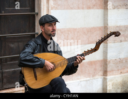 A street musician playing a long-necked lute with a second pegbox ...