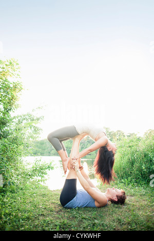 Yoga group practicing partner backbend poses in studio, with mats ...
