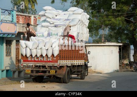 Overloaded Indian lorry carrying sacks of rice and farm workers ...
