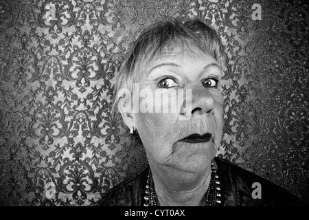 Portrait of snooty senior woman in front of gold background Stock Photo ...