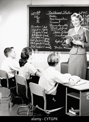 A teacher giving a lesson to a group of children in a classroom, with ...