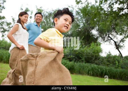 Cheerful family playing sack race Stock Photo - Alamy