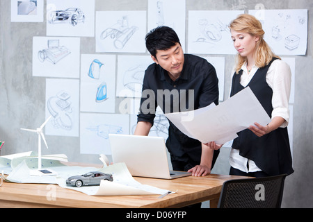 Designers studying blueprint in studio Stock Photo - Alamy