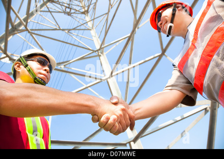 Two power line tower workers with handshaking Stock Photo - Alamy