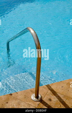 Steps into the pool with handrails in water reflex sun. For tourists ...