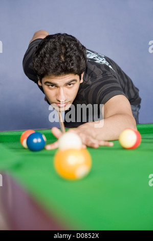 Indian man playing billiards hitting white cue ball on pool table ...
