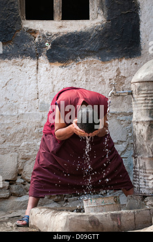 Young Buddhist monk washing with a bucket at the water pump. At Angkor ...