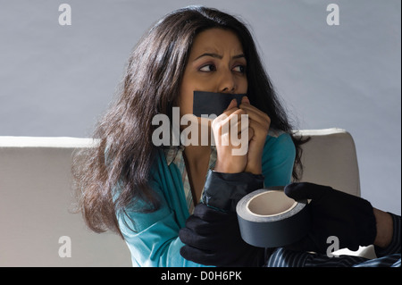 Kidnapper's hands wrapping adhesive tape around an abducted young woman ...