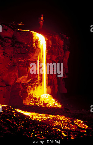 Man Standing by Lava Flowing Over a Cliff Stock Photo - Alamy