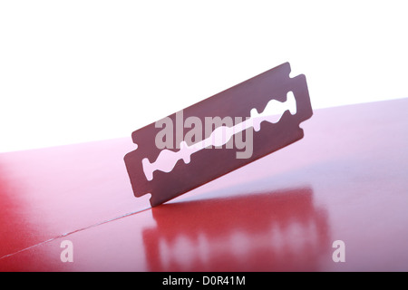 The safety razor cuts a red paper Stock Photo - Alamy