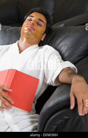 Asian man resting on couch using smartphone while sick at home Stock ...