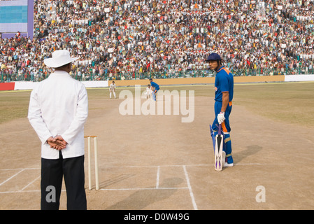 Behind side view of cricket player batting while playing on field in a ...