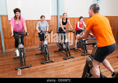 Male instructor leading female spinning class Stock Photo - Alamy