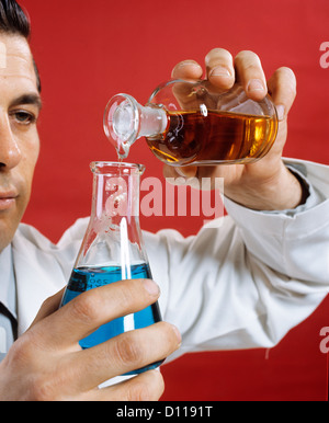 Chemist pouring fluid from flask into Petri dish Stock Photo - Alamy