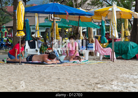 Tourists enjoying a traditional Thai Massage on the Beach of Patong on Phuket Island, Thailand ...