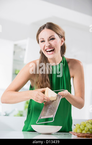 Germany, Young woman grating cheese, smiling Stock Photo - Alamy