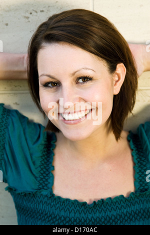 portrait of young smiling germany woman in dress near roses in a garden ...