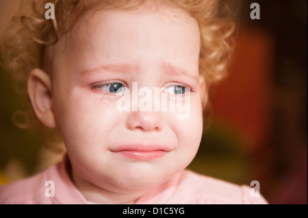 Little curly haired girl crying in her room. Little girl misses it`s ...