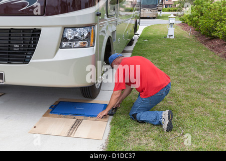 Man places portable scale in position to weigh motor coach at RV resort ...