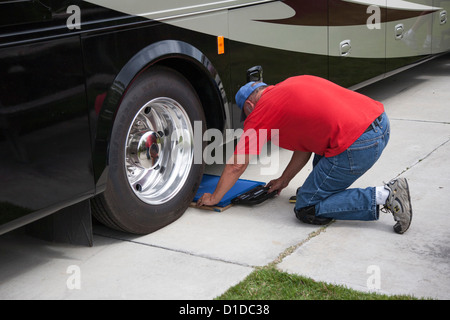 Man places portable scale in position to weigh motor coach at RV resort ...