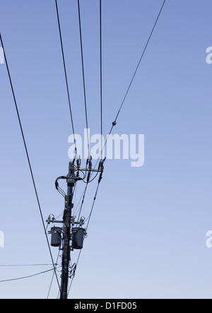 A vertical low angle shot of an Utility pole with cris cossing wires ...