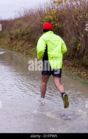 Flood water running down a road into an overflowing grate by the kerb ...