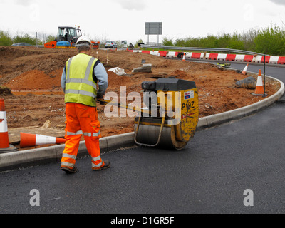 Roadworker operation a self propelled roller on binder course asphalt ...