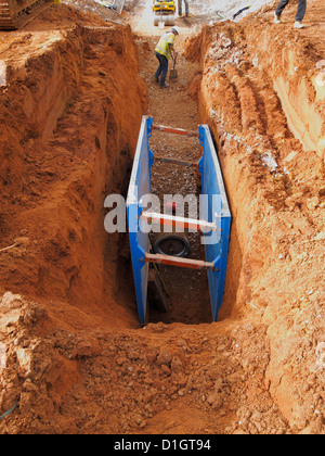 Men working in deep trench excavation under protection of hydraulic ...