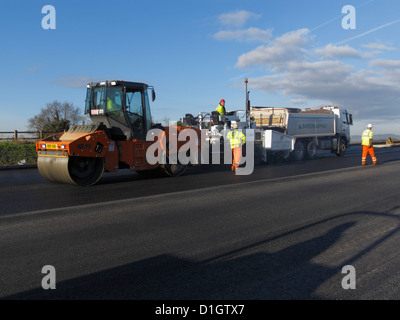 A road paver & tipper truck laying tarmac on the first phase of the ...