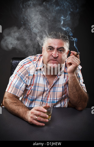 Portrait of a mature mafia man drinking and smoking while sitting at ...