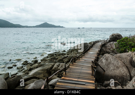 Rickety boardwalk and wooden pier and stormy sea with boat in ...