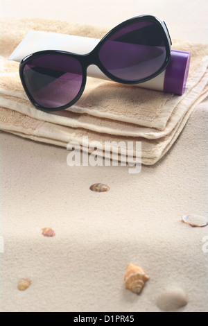 Suncream and sunglasses on a beach towel Stock Photo - Alamy