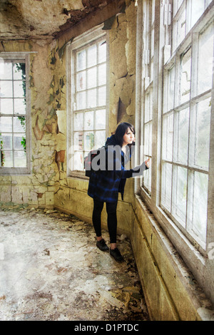 Scared woman looking out of a window Stock Photo - Alamy