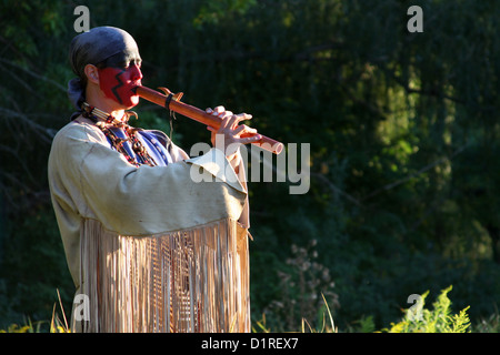 A Native American Indian man playing a flute outside in nature Stock ...
