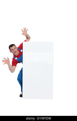 Scary builder jumping out from behind poster Stock Photo - Alamy