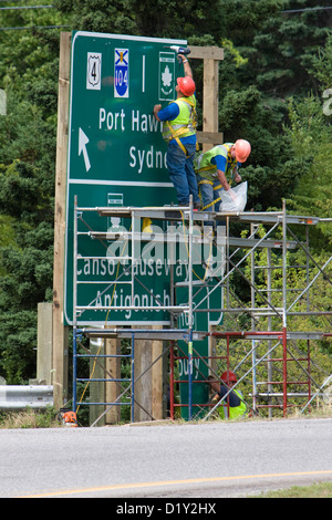 Workmen repairing the sign to the Canso Causeway in Nova Scotia, Canada ...
