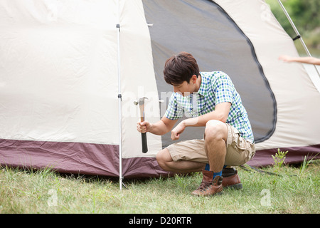 father using hammer to build a tent Stock Photo - Alamy